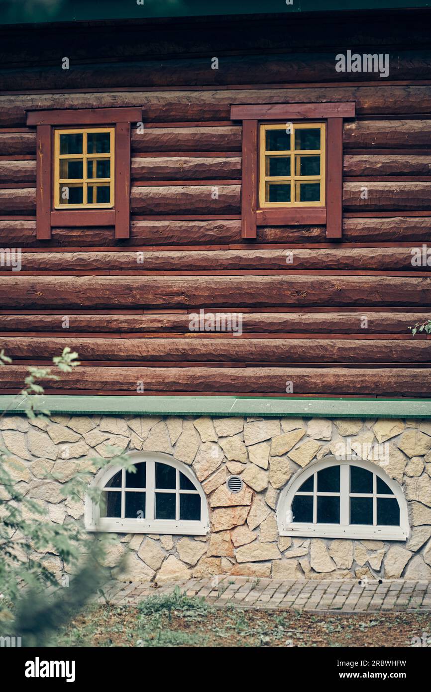 The facade of the building has four windows. One part is made of logs ...