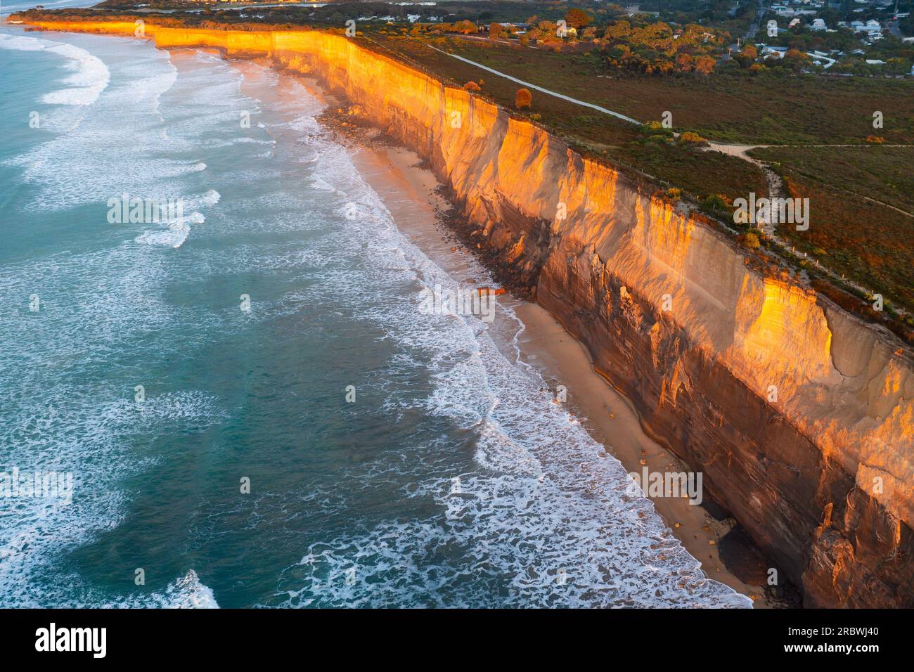 Aerial view of waves crashing at the base of high sea cliffs at ...