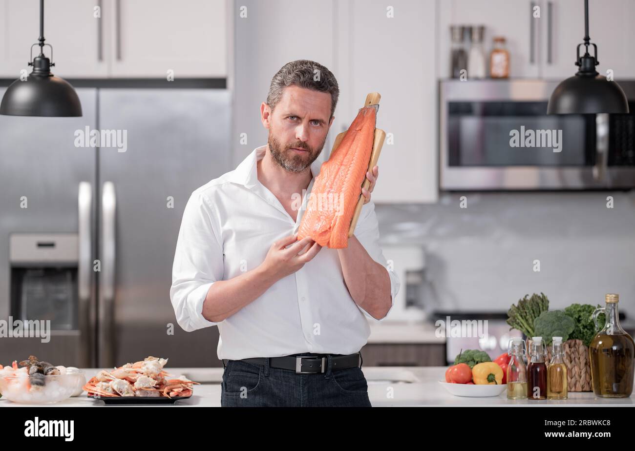 Man in modern kitchen preparing fish salmon. Handsome man is cooking ...