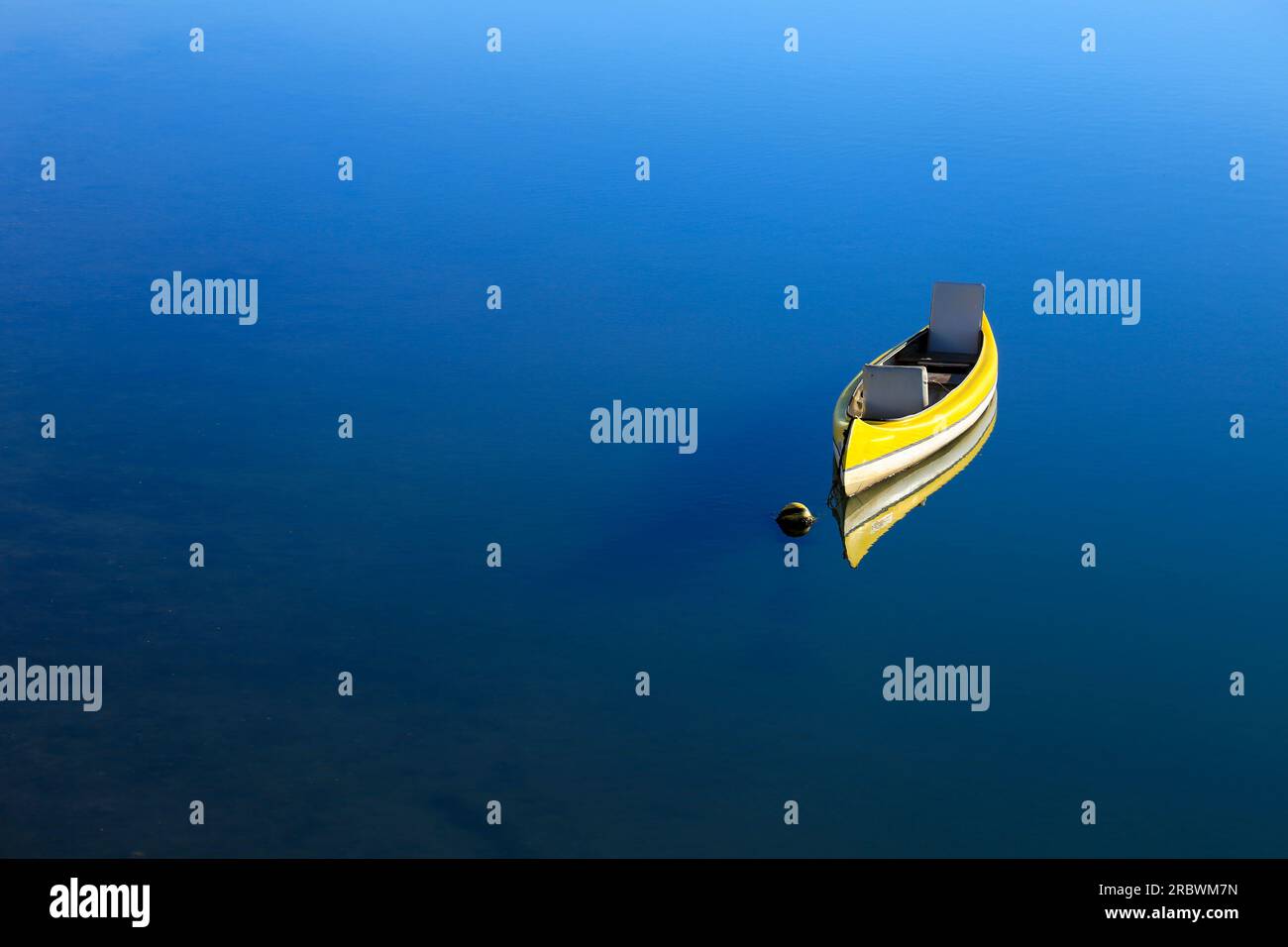 Beautiful Yellow canoe anchored on calm blue water Stock Photo - Alamy