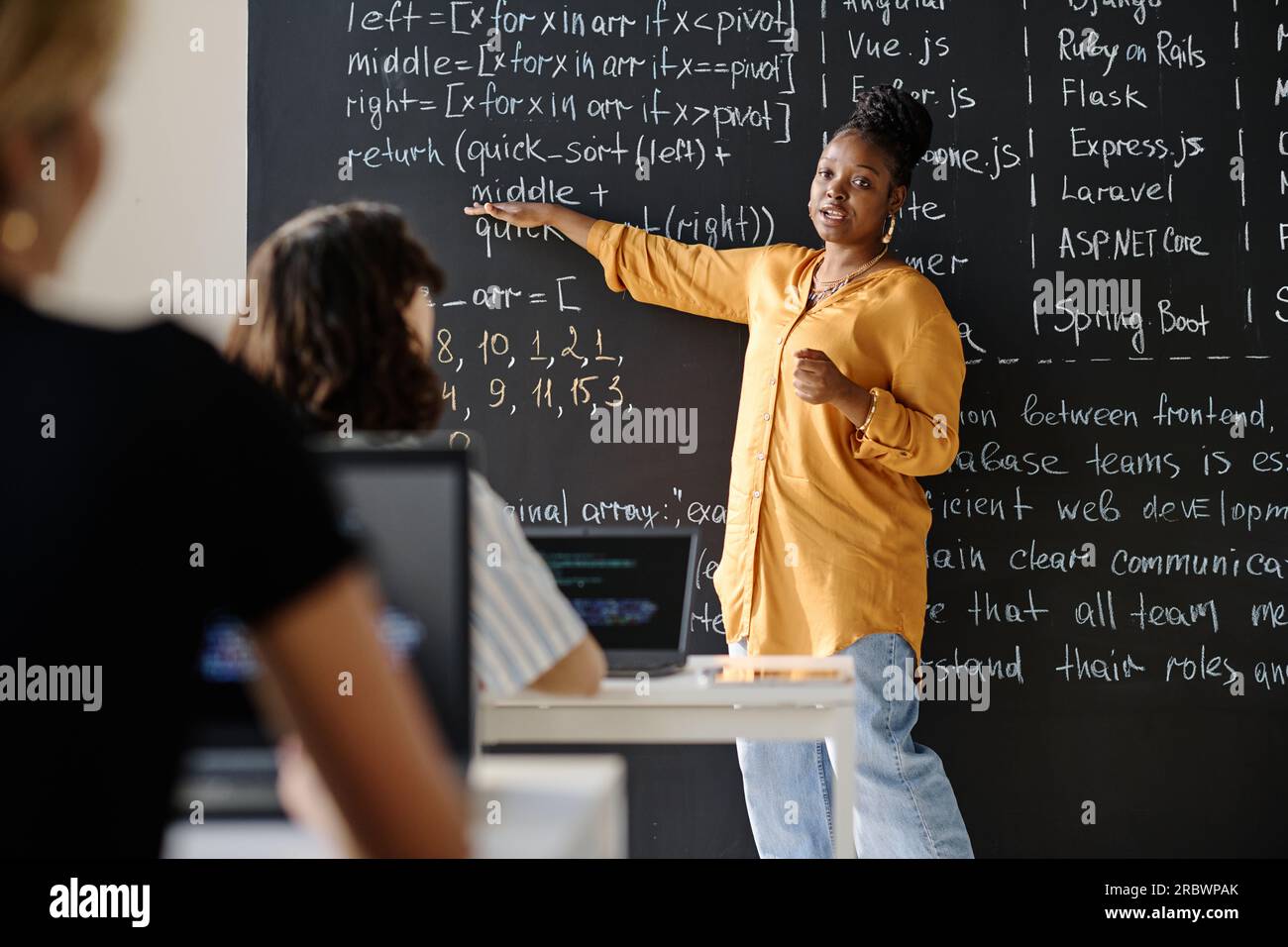African American teacher pointing at blackboard with IT formulas and ...