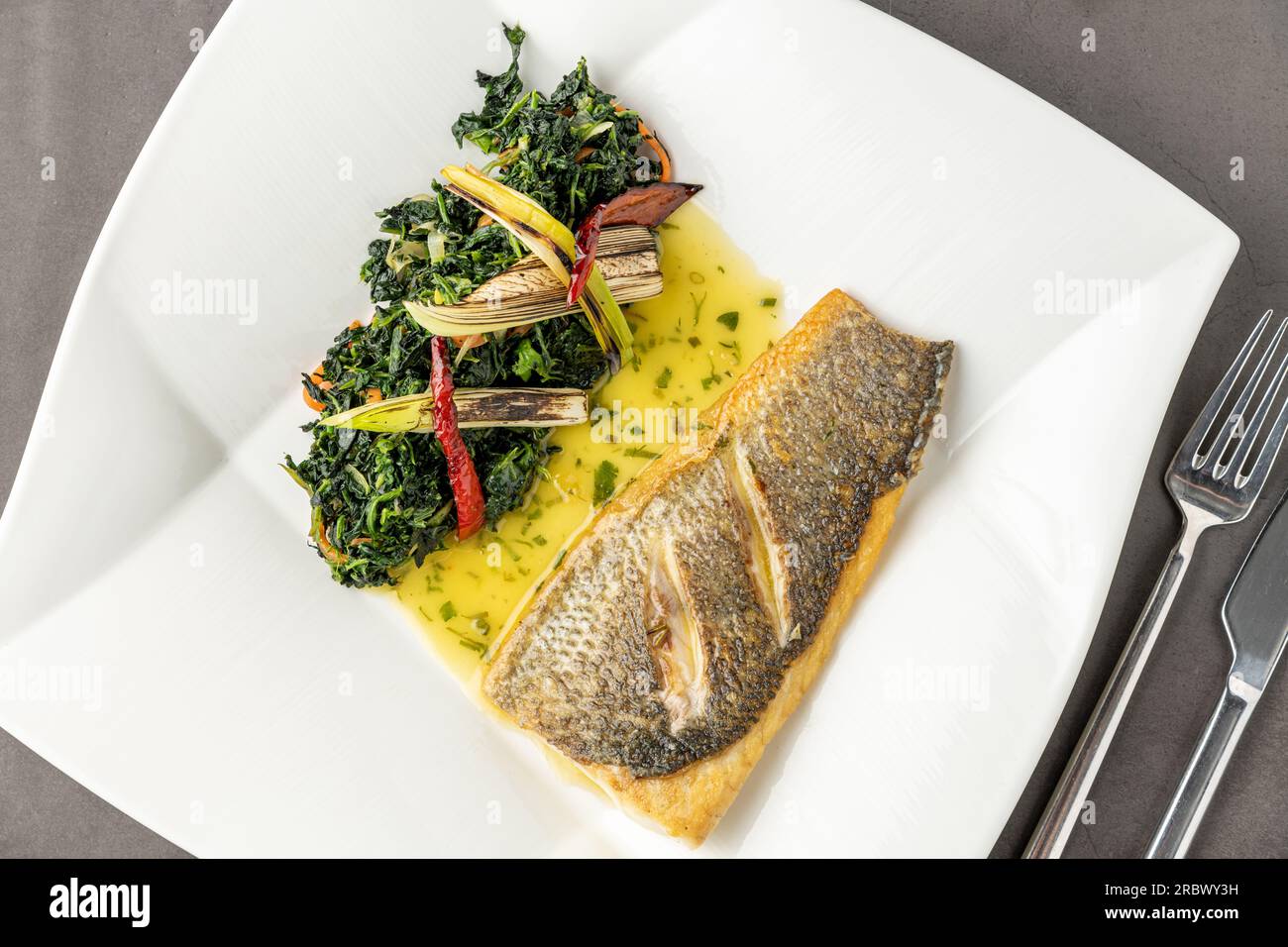 Grilled sea bass fillet served with garnishes in a fine dining ...