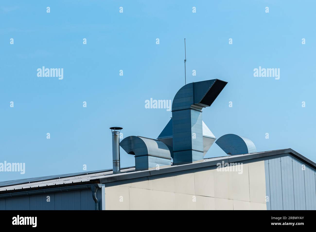Metal exhaust ventilation pipes on the roof of a building under a blue ...