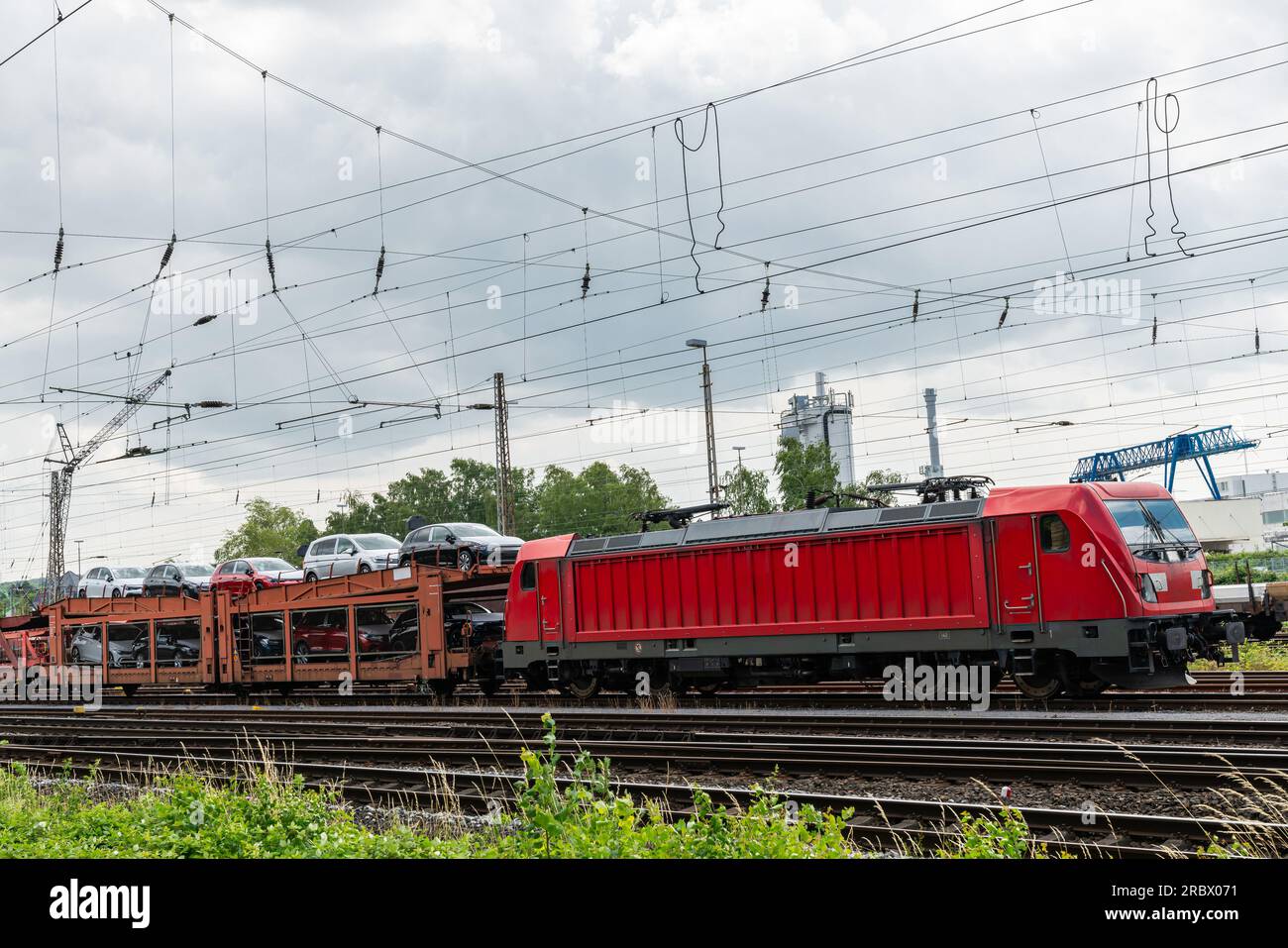 Red locomotive pulling railway wagon with autocars.. The sky at the ...