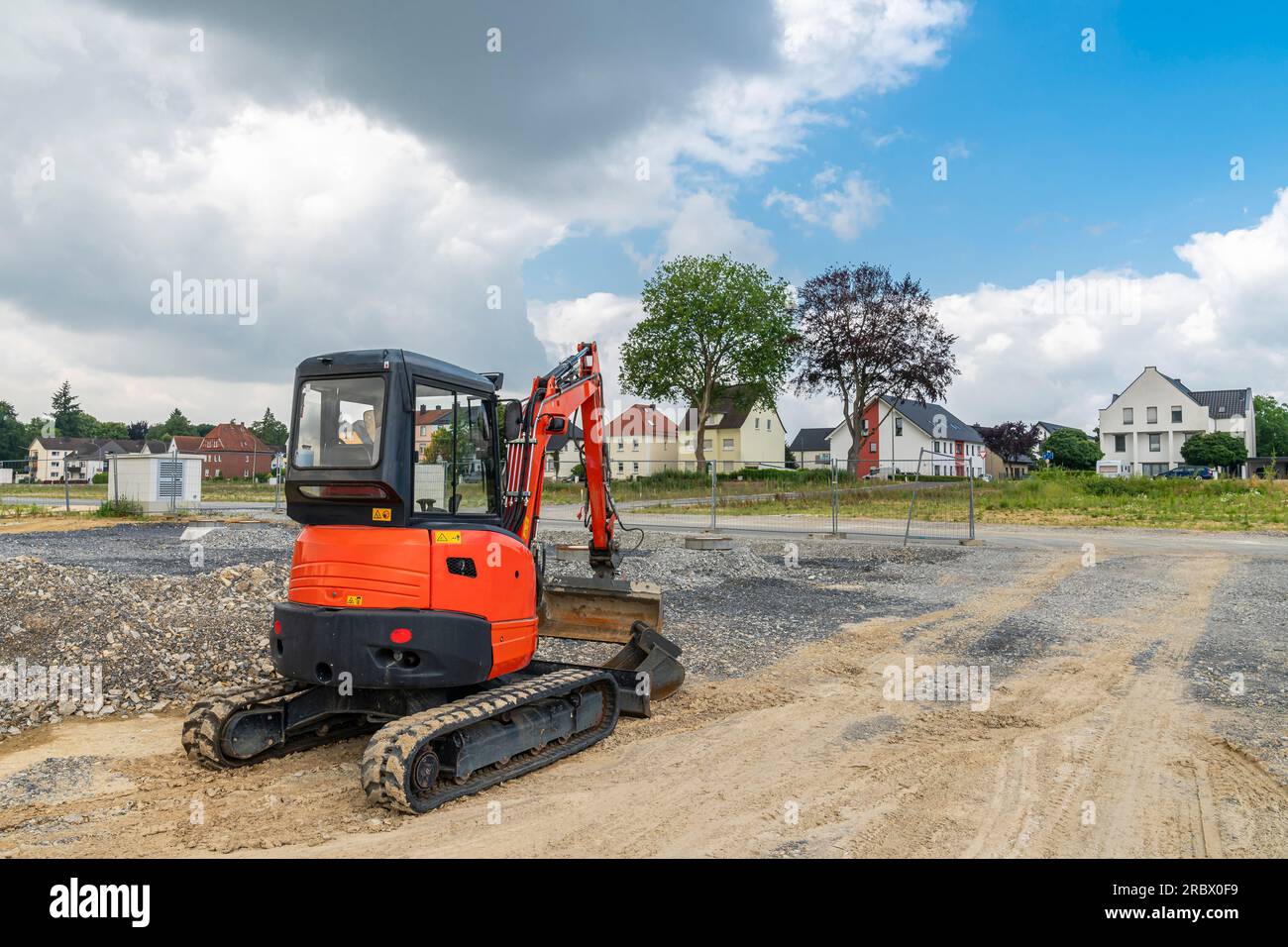 Rear view of a small red excavator standing on the edge of a ...