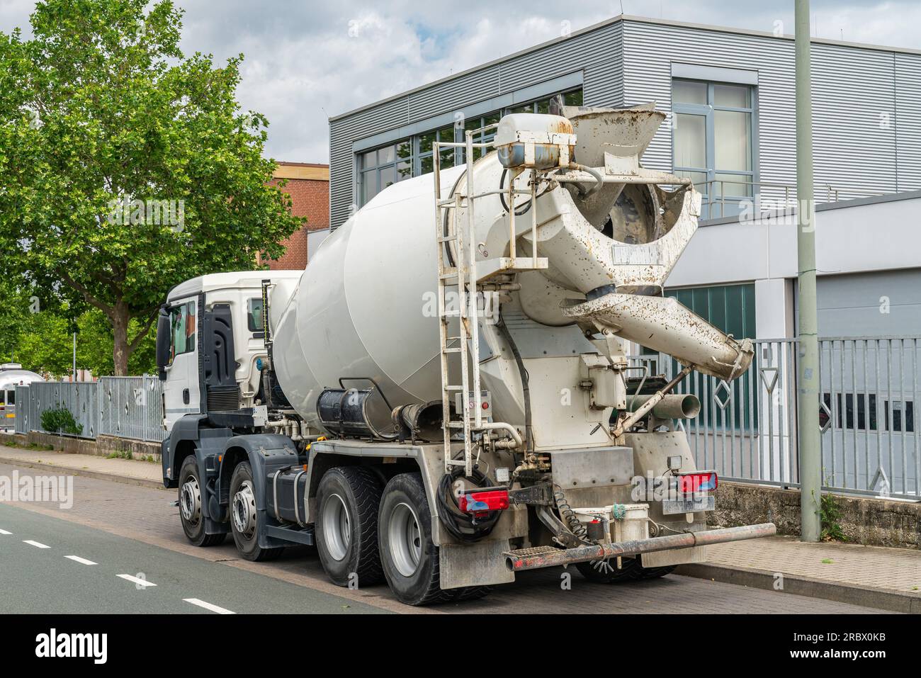 A large car with a concrete mixer stands on the side of the city road ...
