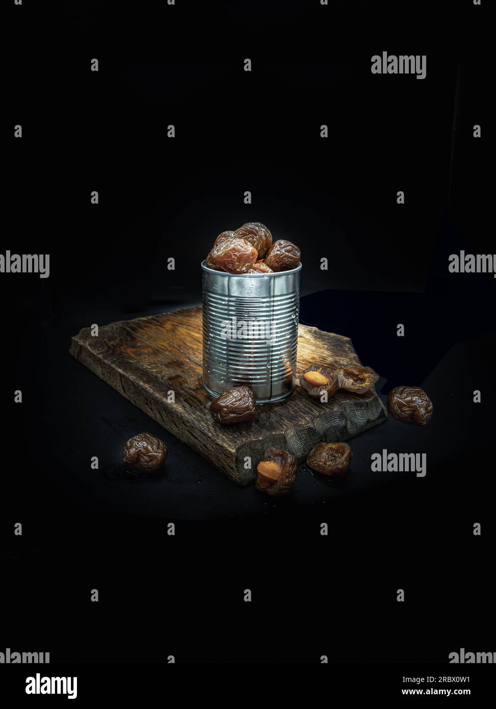 Flavored preserved chinese plums (Preserved fruits) in tin can on dark ...