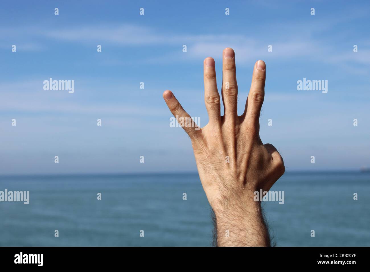 Hand doing,showing number four gesture symbol on blue summer sky nature ...