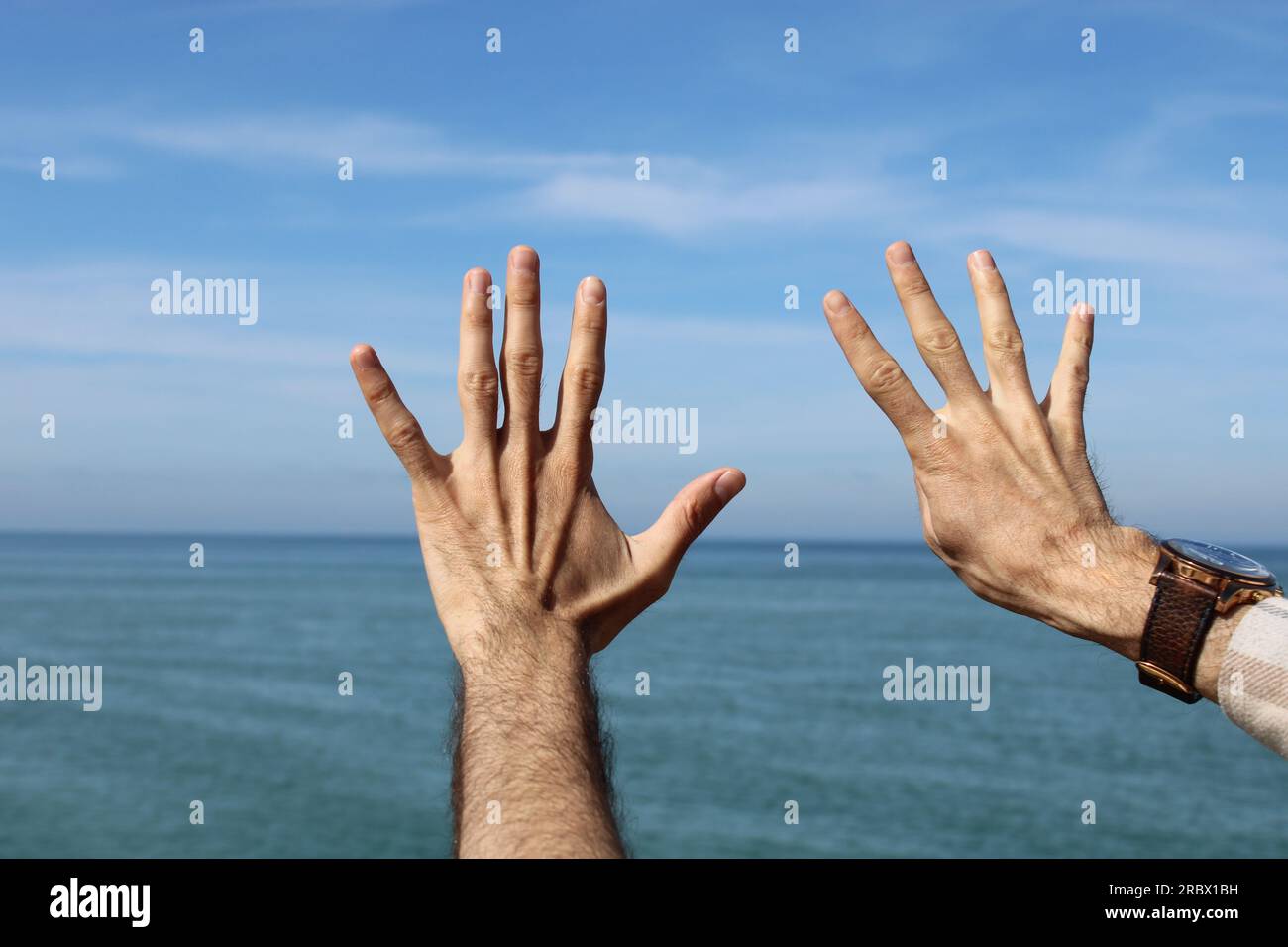 Hand doing,showing number gesture symbol nine on blue summer sky nature ...