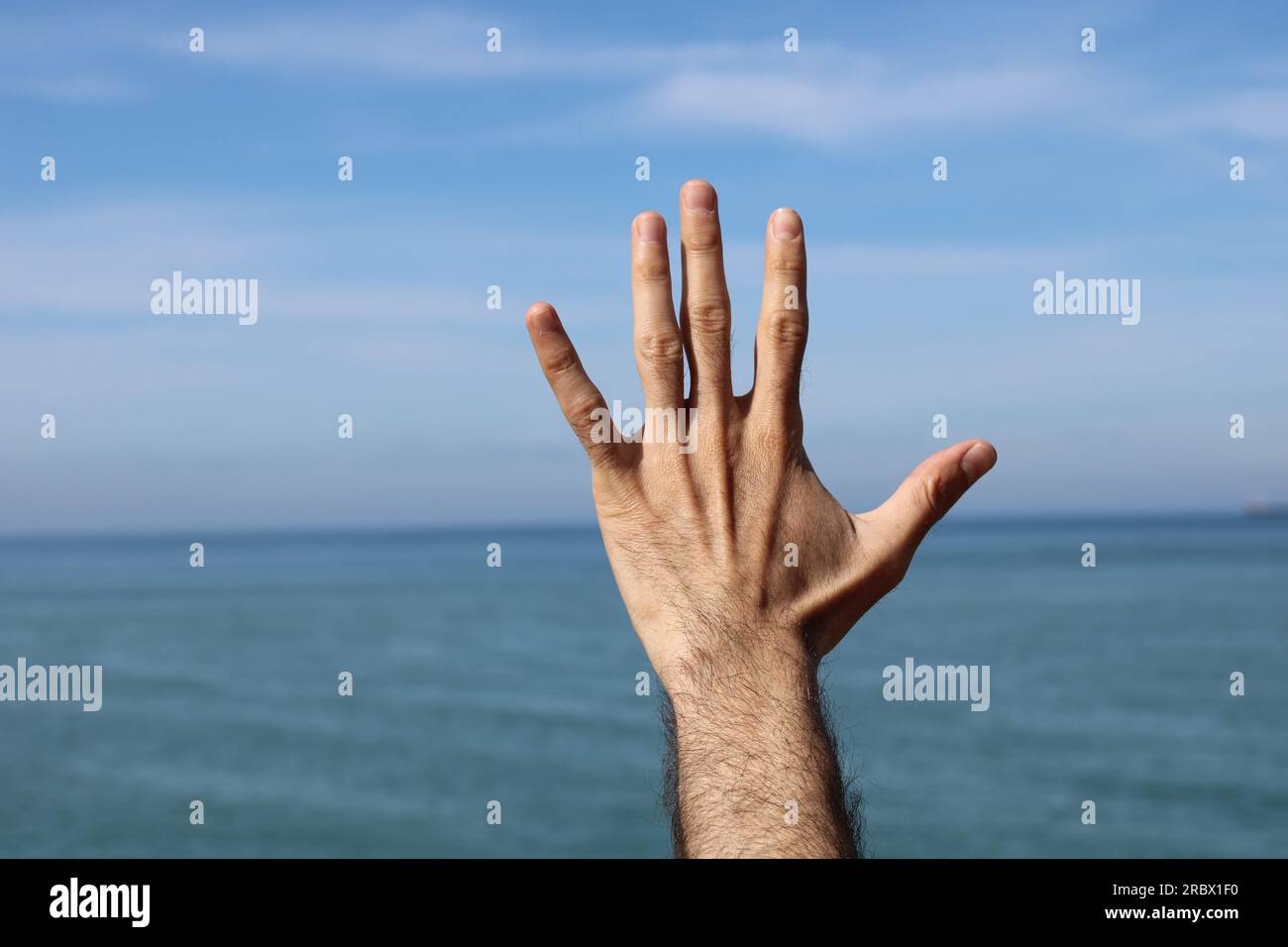Hand doing,showing number five gesture symbol on blue summer sky nature ...