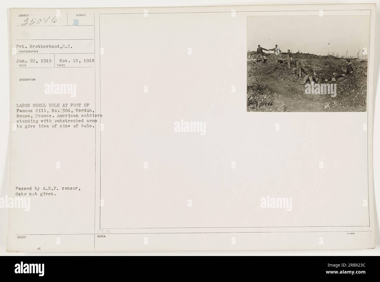 American soldiers standing near a large shell hole at the foot of ...