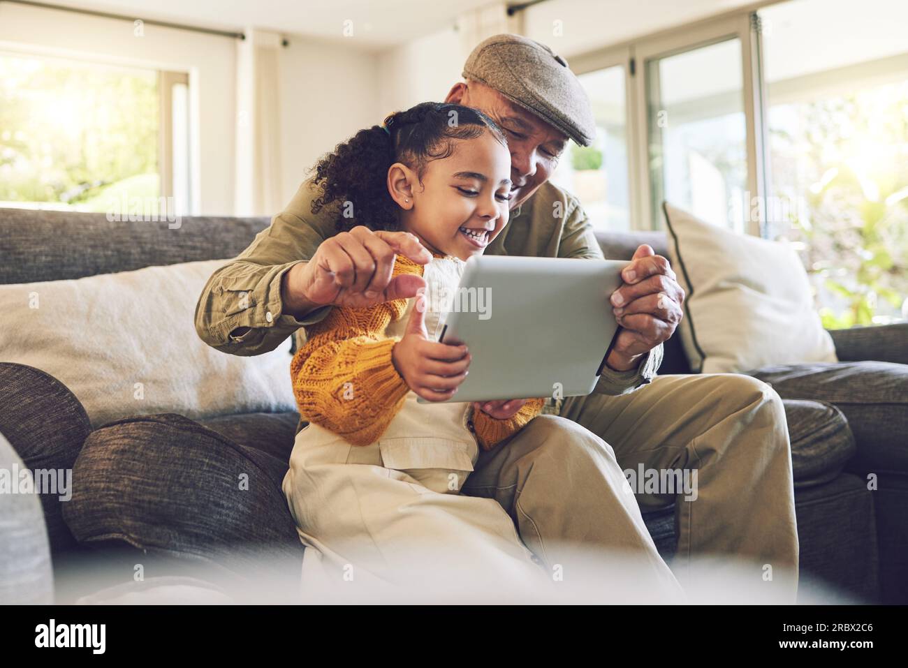 Young girl, grandfather and tablet, games and entertainment, watch cartoon or e learning while ...