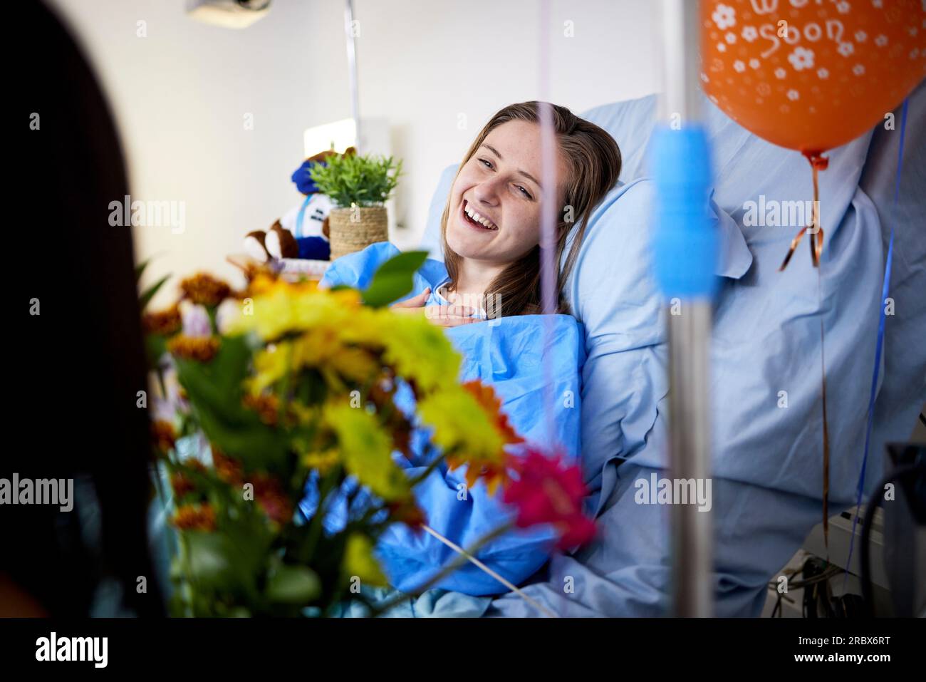 Hospital, sick patient and visitor with flowers at bed with a woman in ...