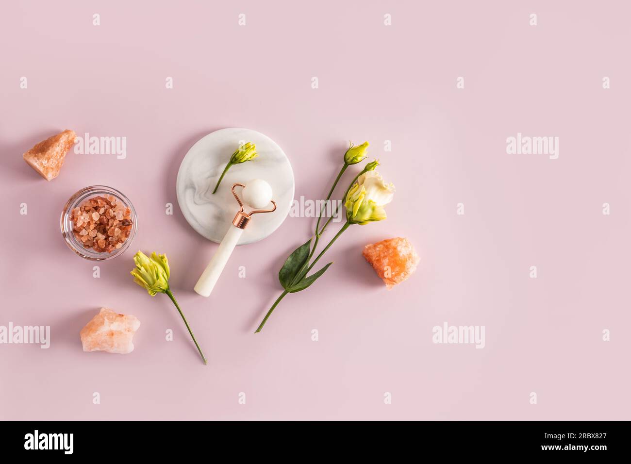 A professional rose quartz massager for facial care at home lies on a ...