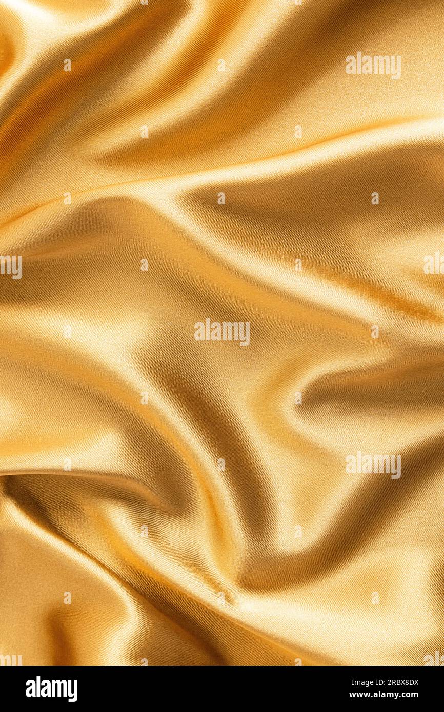 The texture of the satin golden color fabric. golden soft waves of ...