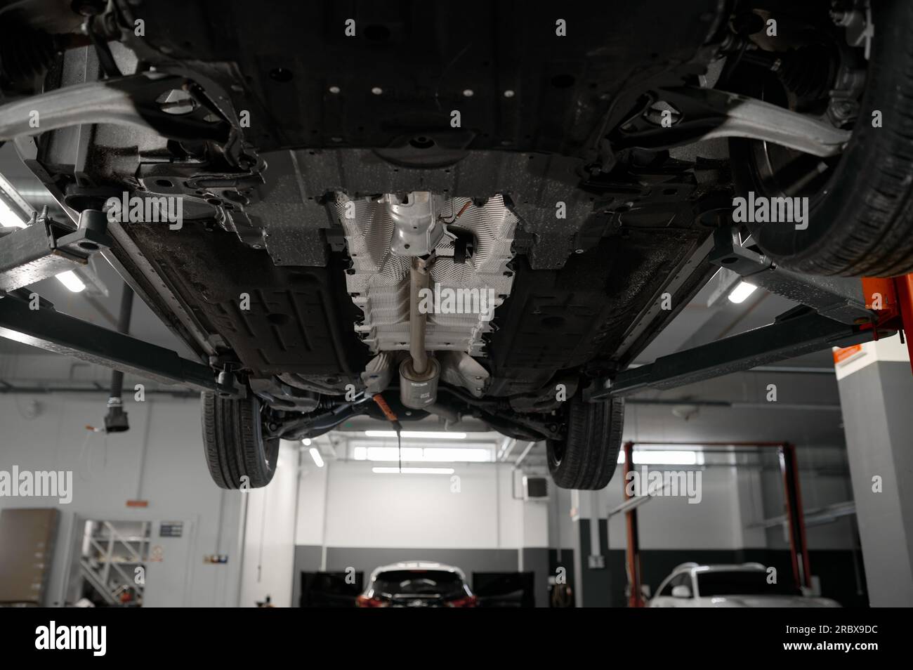 Bottom view of raised car on lift in repair garage Stock Photo - Alamy