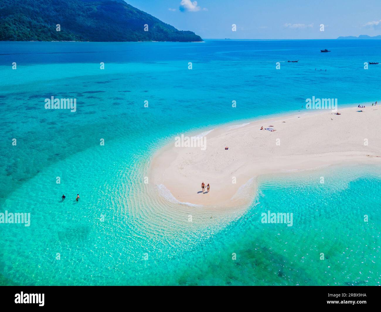 men and women walking on a sandbar in the ocean of Koh Lipe Southern ...