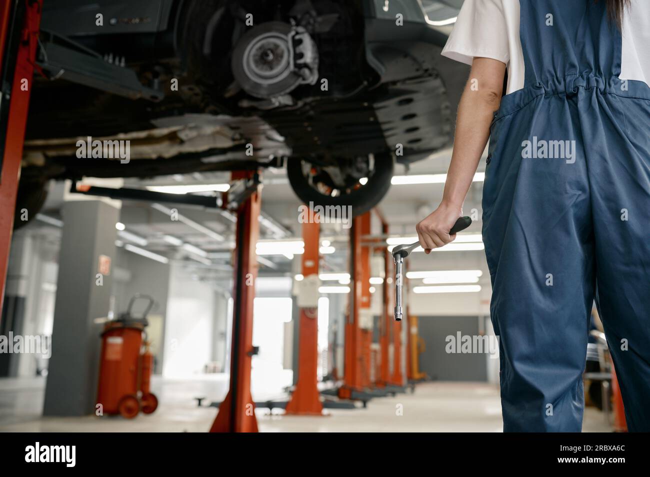 Back cropped view on female mechanic hand holding spanner wrench tool ...