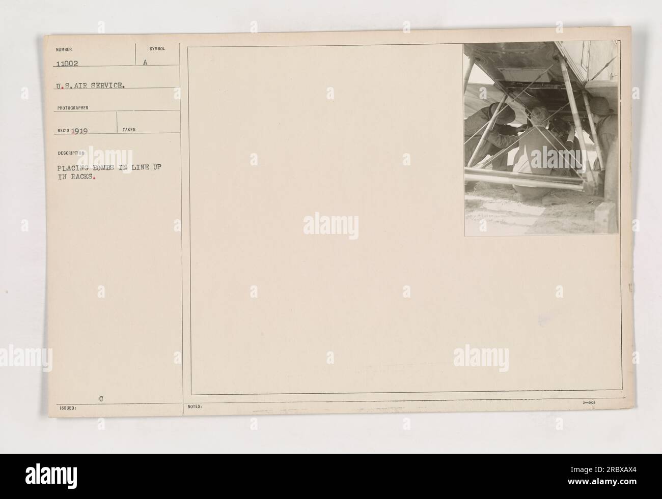 Soldiers placing bombs in line up on racks. This photograph was taken ...