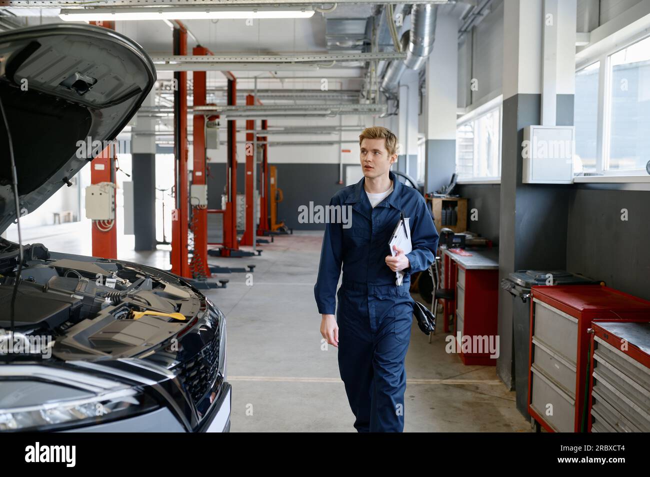 Professional handsome male car mechanic walking along service station ...