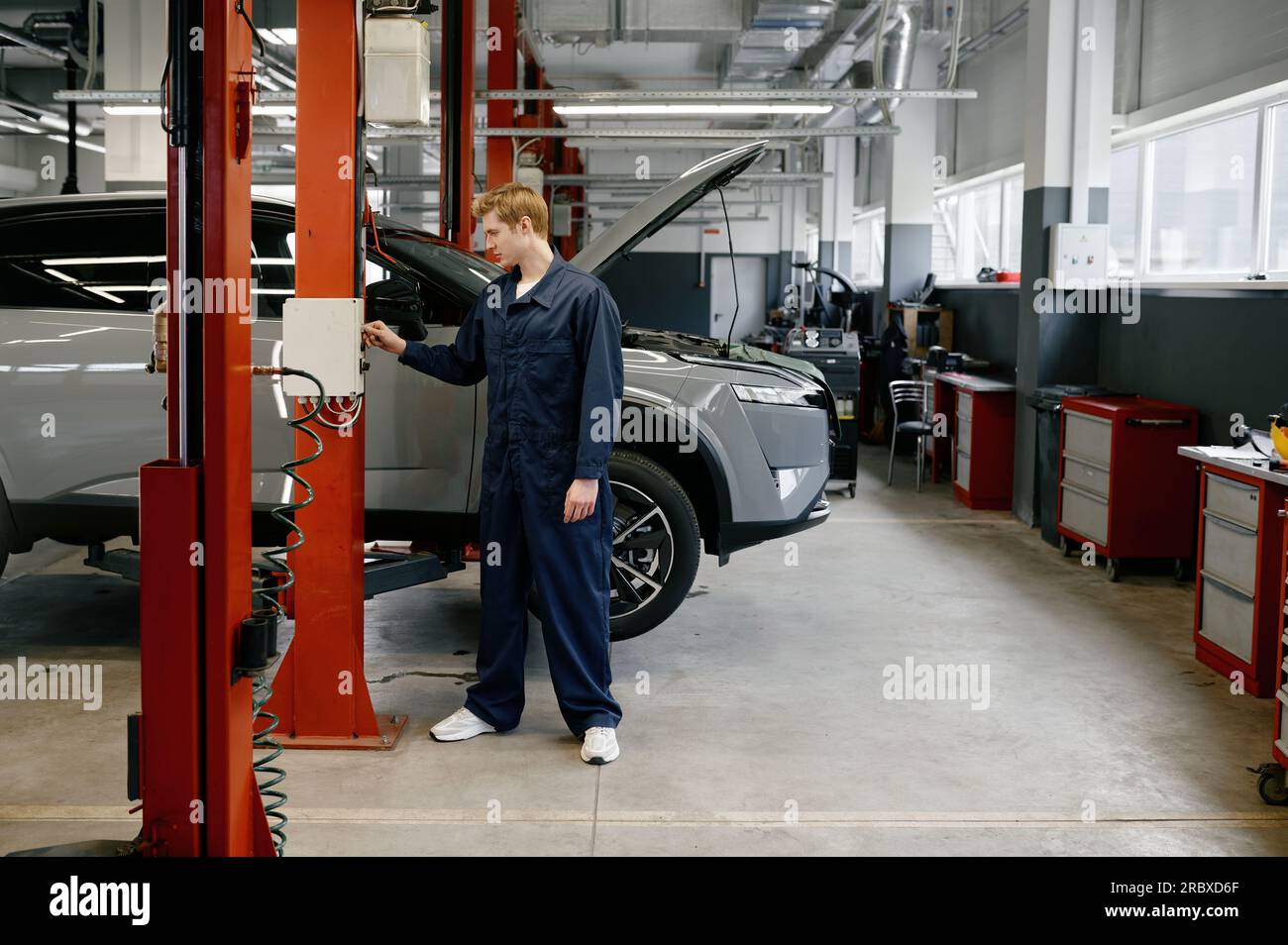 Man mechanic turning on automated car lift working repair service Stock ...