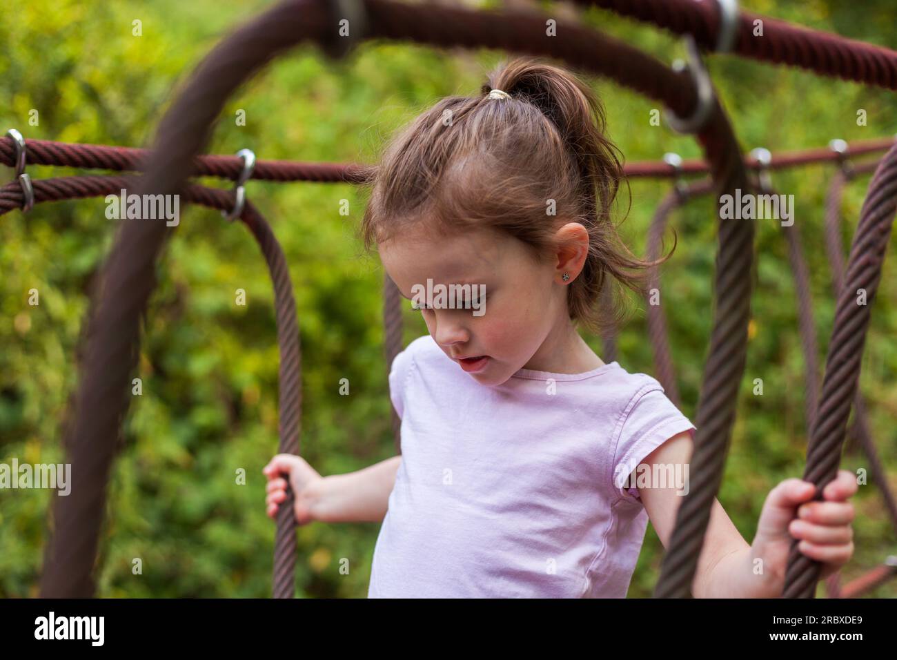 Adorable little girl having fun on a rope playground in the park Stock ...