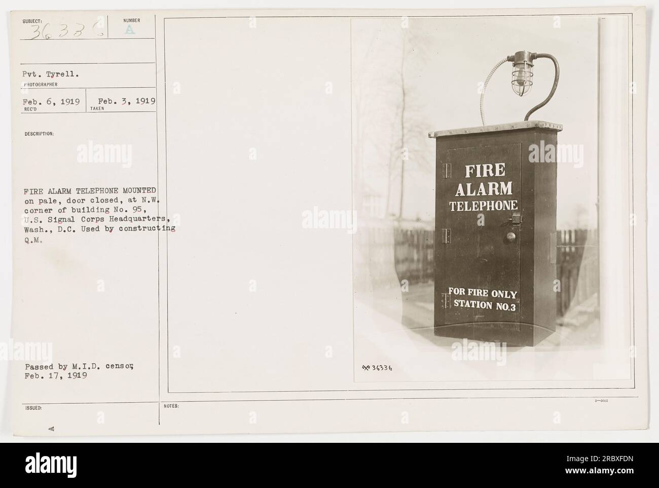 Private Tyrell stands next to a fire alarm telephone mounted on a pale ...