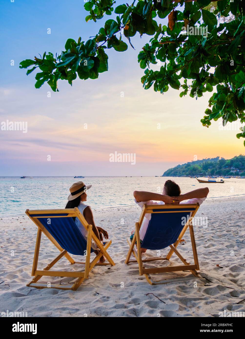couple relaxing at a beach chair on the beach of Koh Lipe Thailand ...
