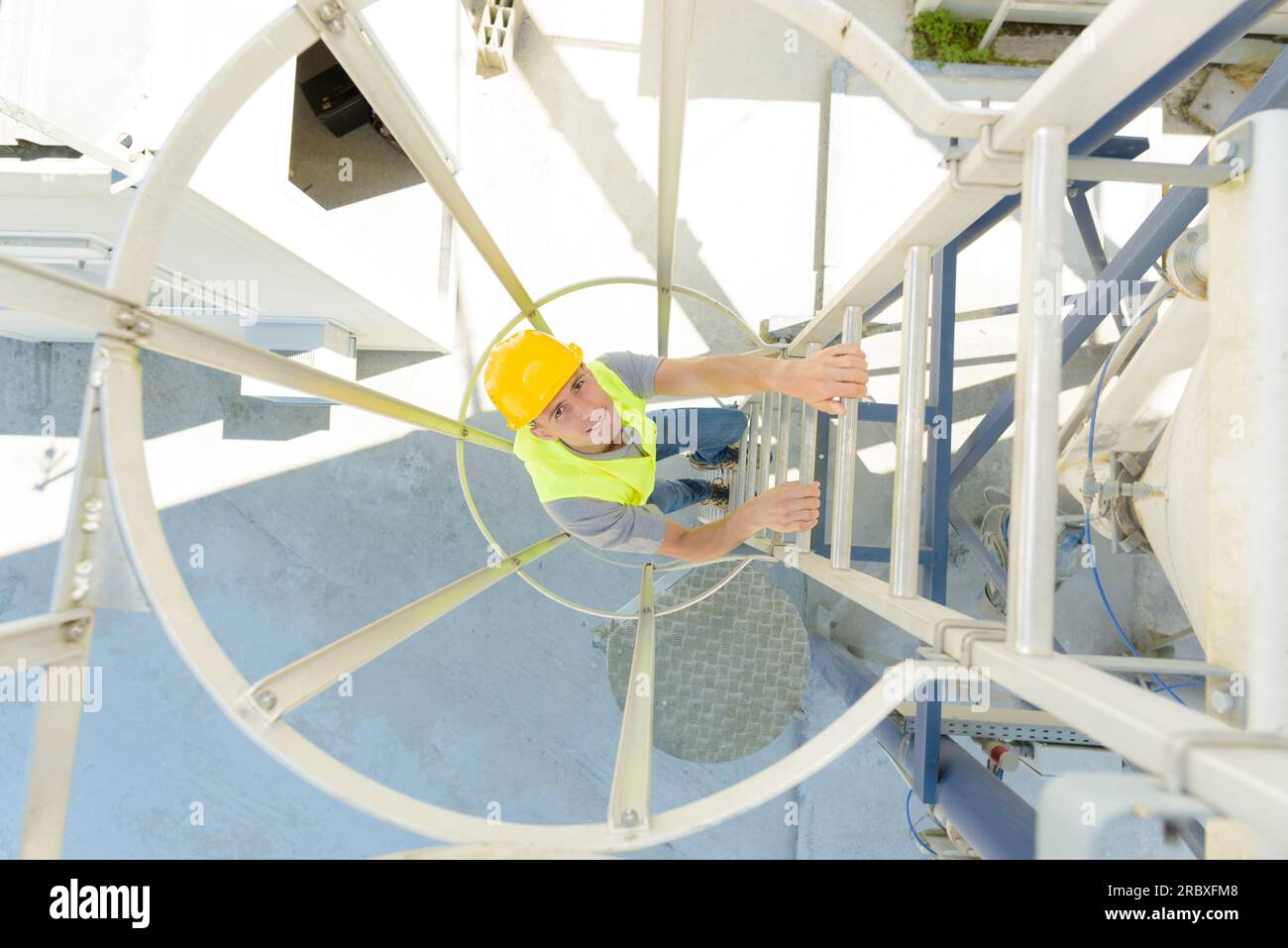 man climbs up an vertical ladder factory Stock Photo - Alamy