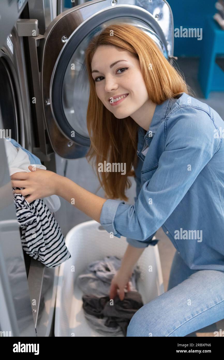 woman doing laundry reaching inside washing machine Stock Photo - Alamy