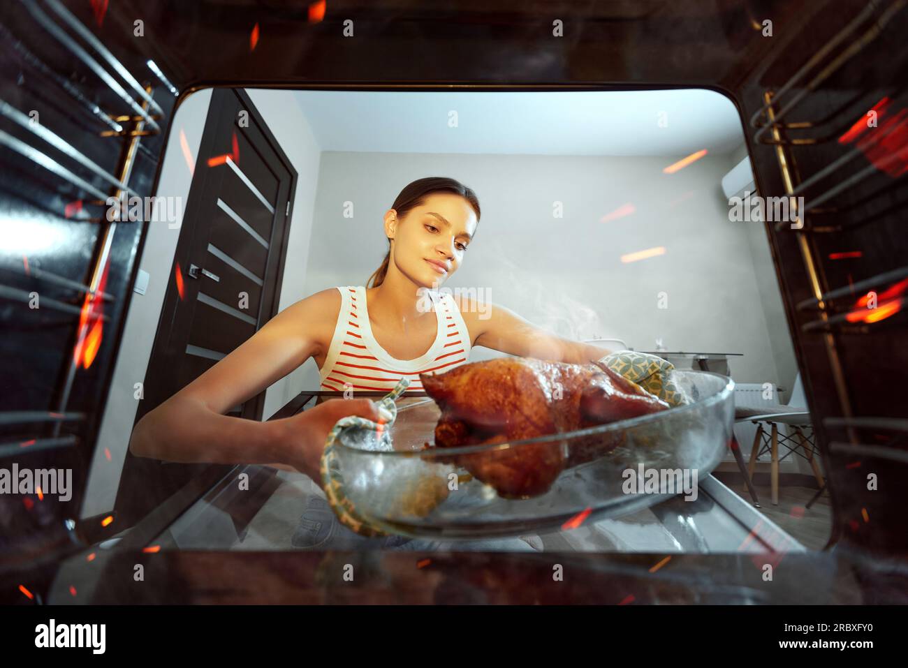 Beautiful young woman cooking dinner, preparing delicious baked chicken ...