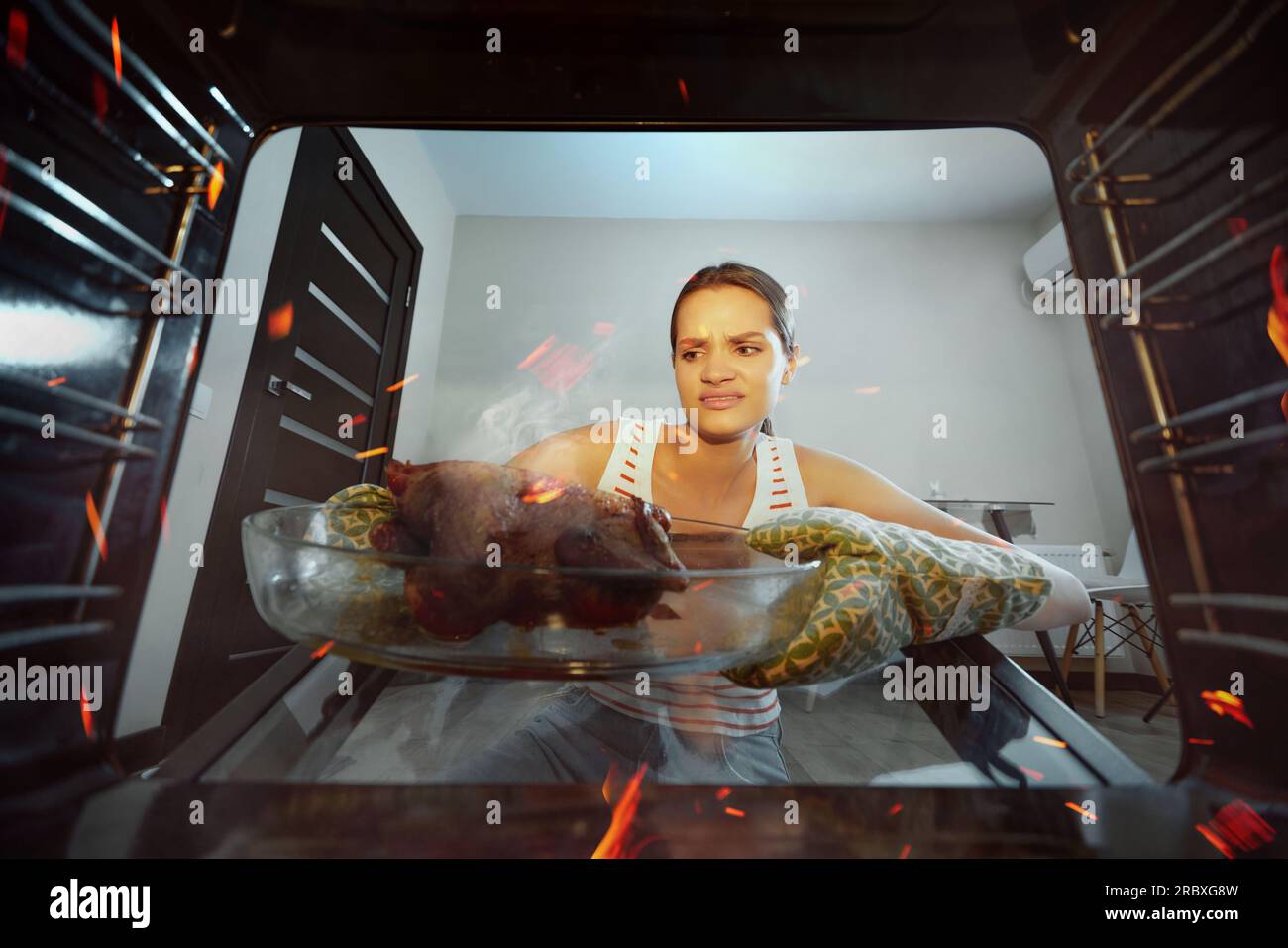 Young woman cooking dinner at home, preparing baked chicken. Overcooked ...