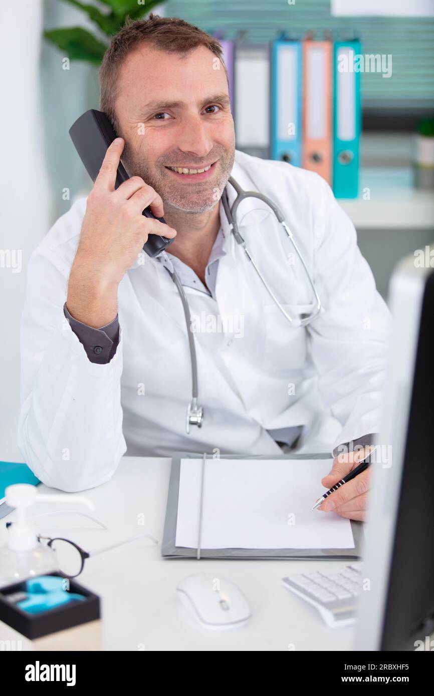doctor at his desk talking on the telephone Stock Photo - Alamy