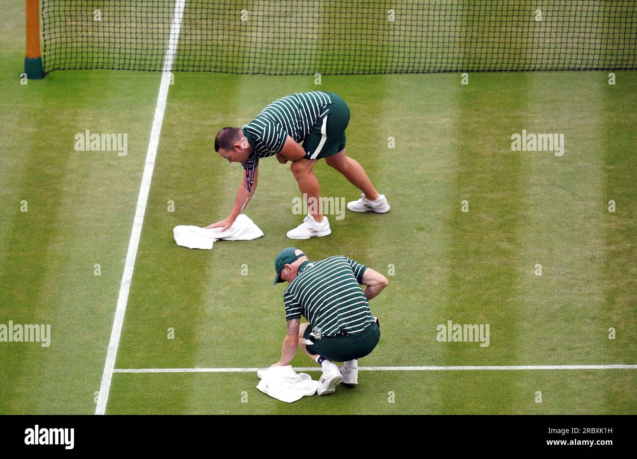 Ground staff dry the playing surface as rain stops play on court one on ...