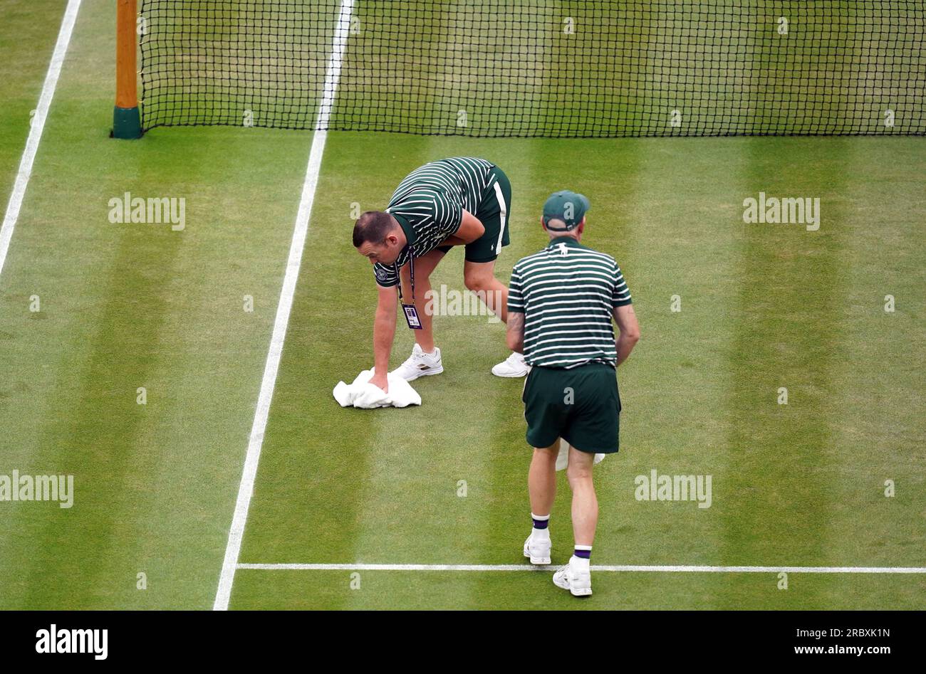 Ground staff dry the playing surface as rain stops play on court one on ...