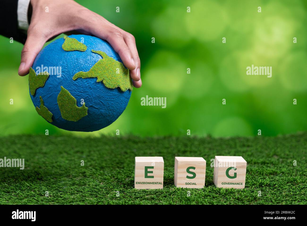 Businessman holding paper earth planet with ESG symbol wooden cube ...