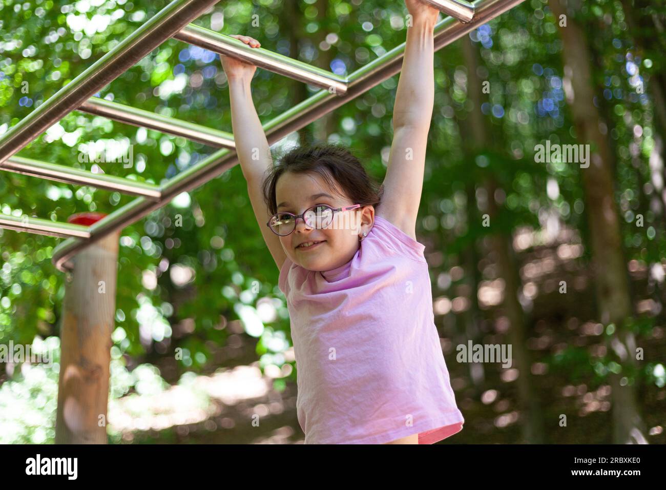 Little girl doing gymnastic exercises on the monkey bars in the park Stock Photo - Alamy