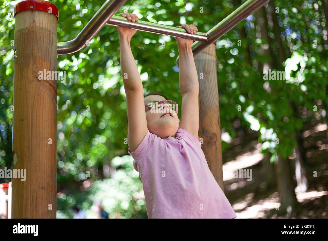 little girl doing pull-ups on the monkey bars in the park Stock Photo - Alamy