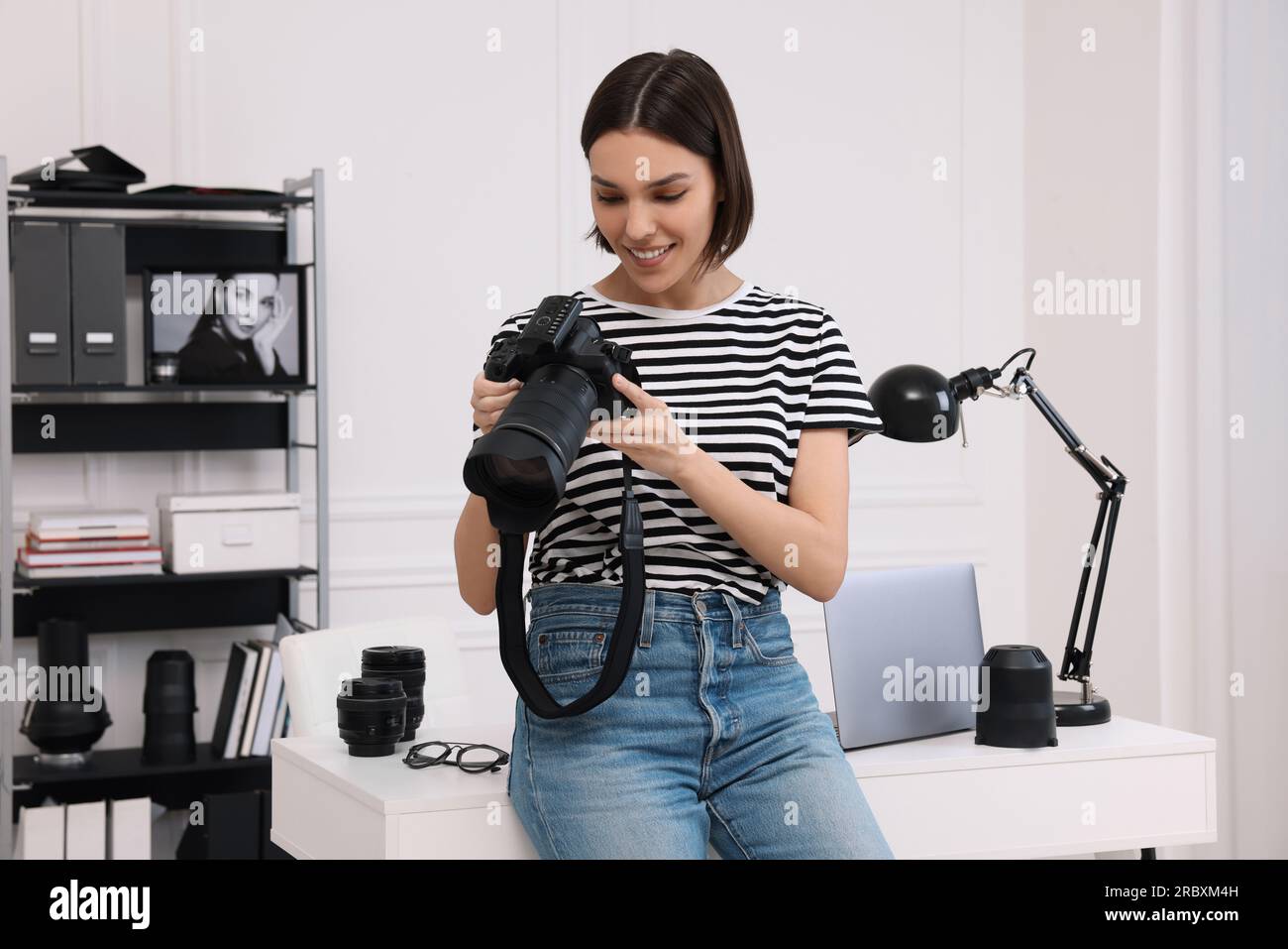 Young professional photographer with camera in modern photo studio ...