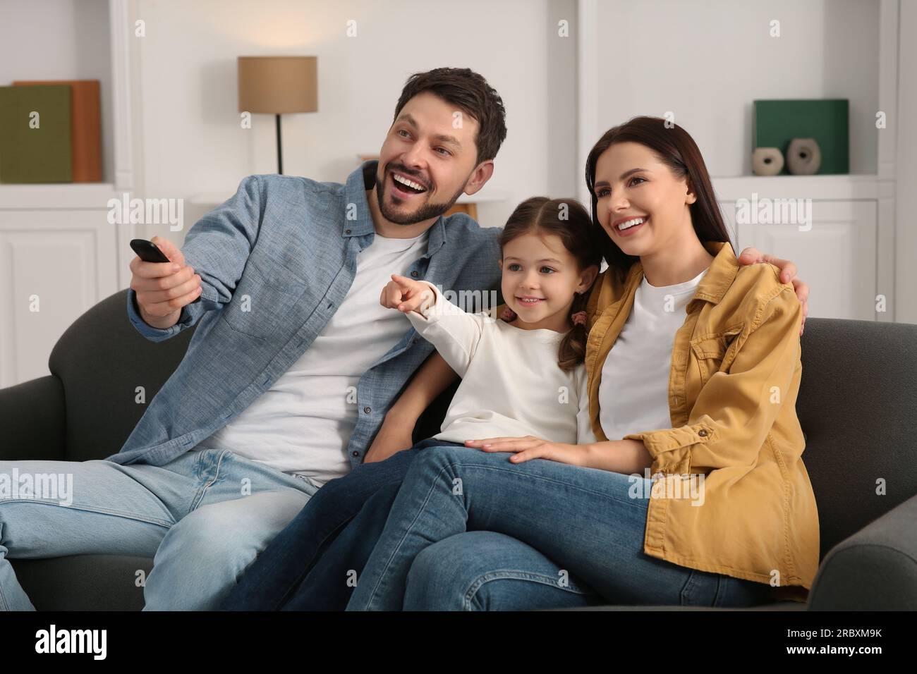 Happy family watching movie at home. Father changing TV channels with ...