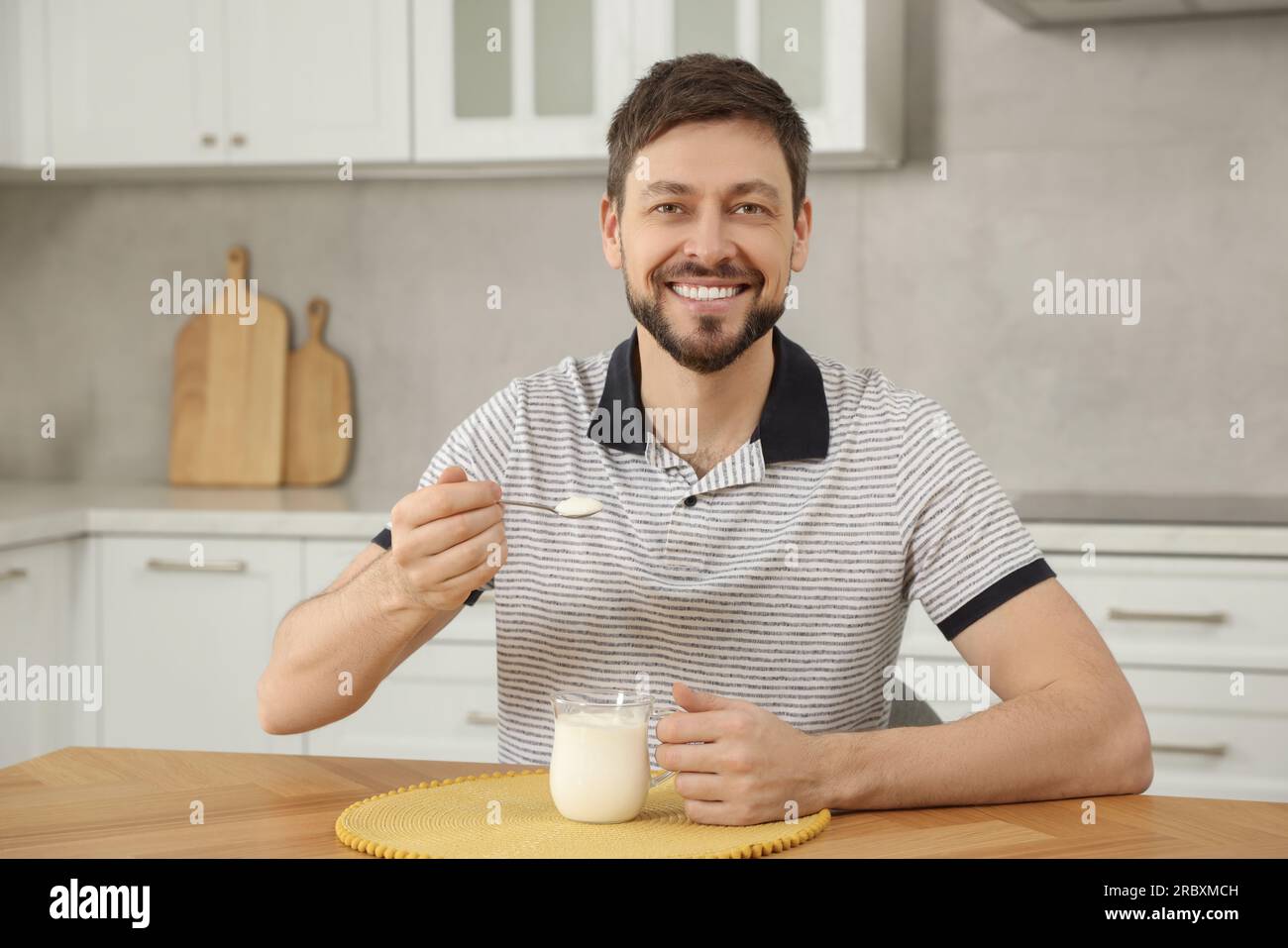 Man eating yogurt in kitchen hi-res stock photography and images - Alamy