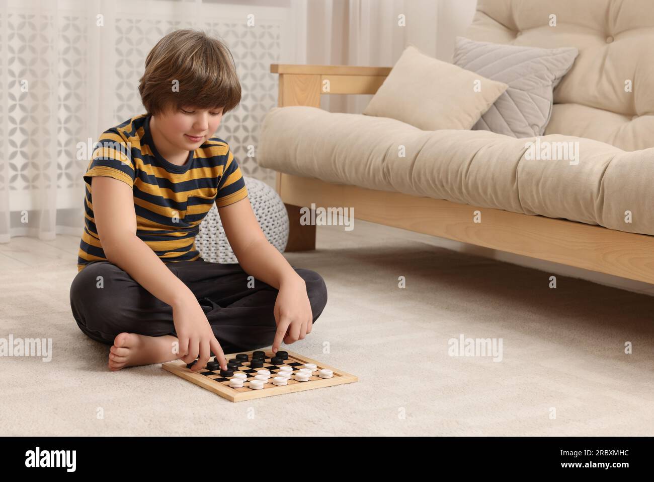 Playing checkers. Concentrated boy thinking about next move on floor in ...