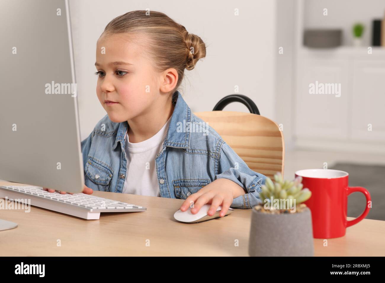 Little girl using computer at table in room. Internet addiction Stock ...
