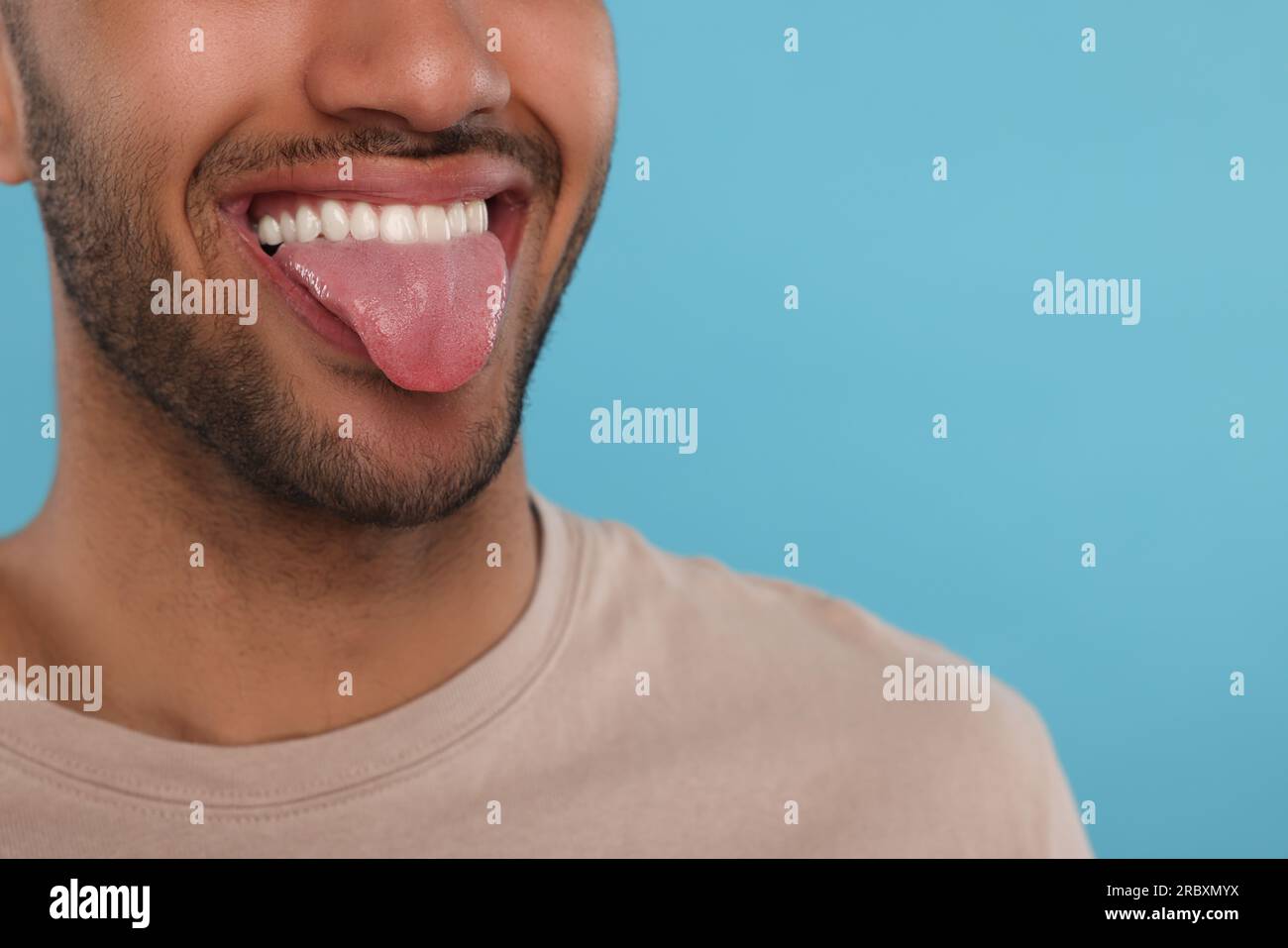Happy man showing his tongue on light blue background, closeup. Space ...