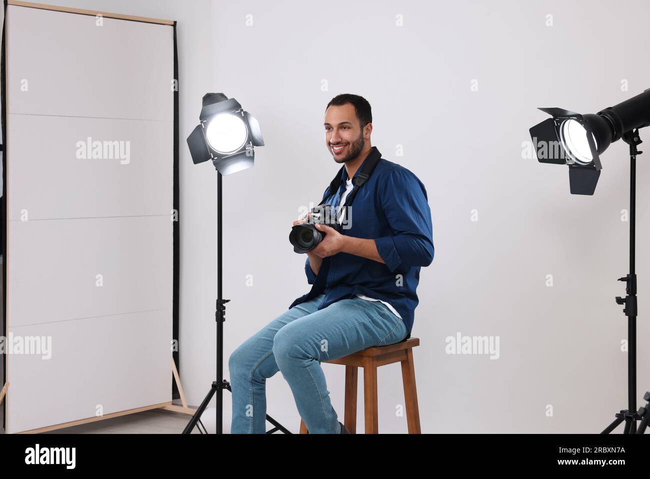 Young professional photographer with camera in modern photo studio ...