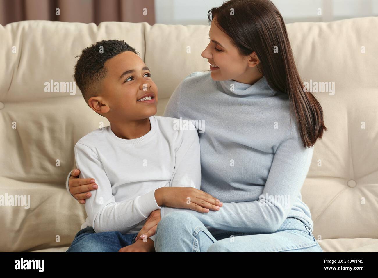 Mother with her African American son on sofa. International family ...