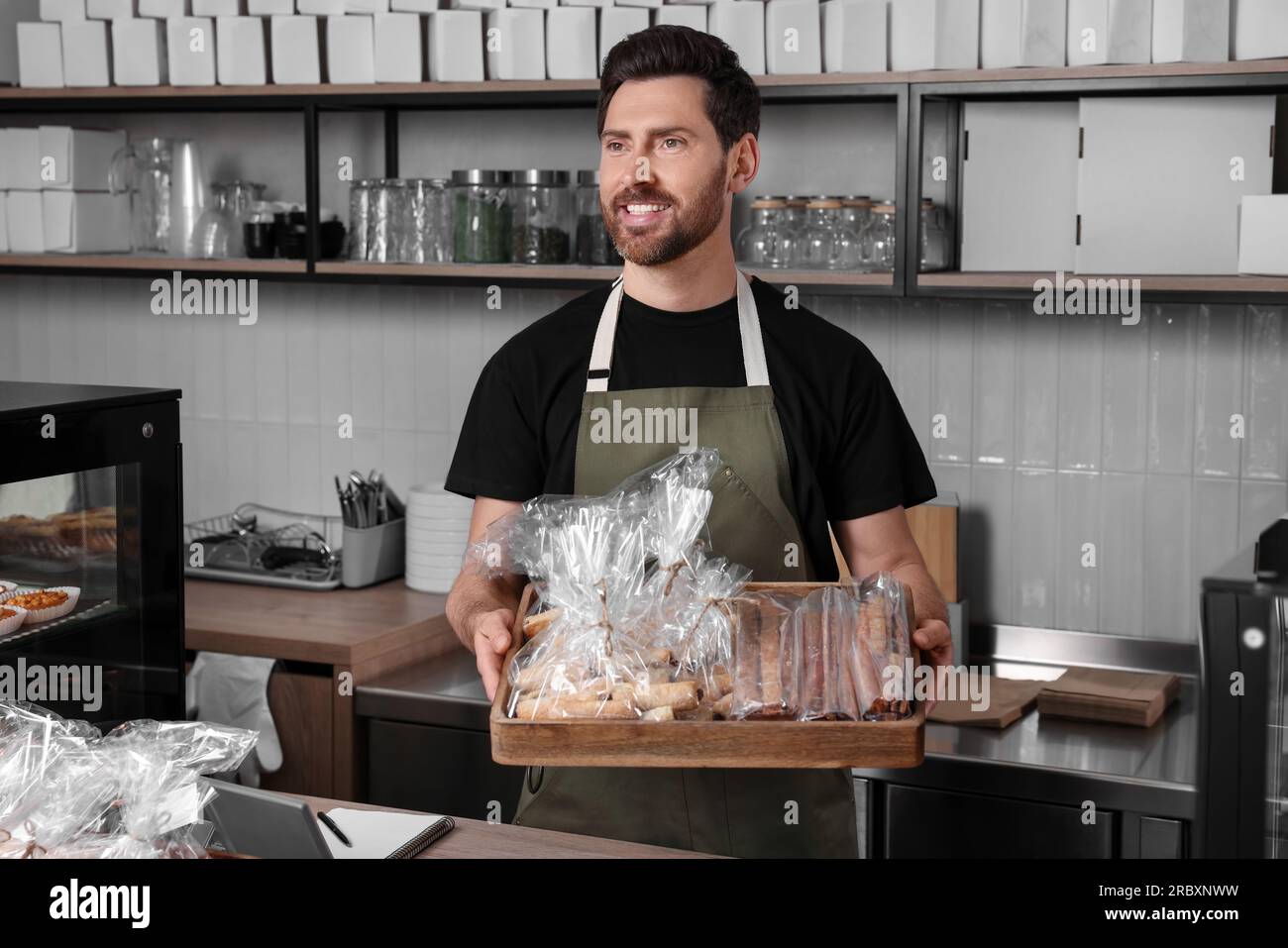 Happy seller with pastries at cashier desk in bakery shop Stock Photo ...
