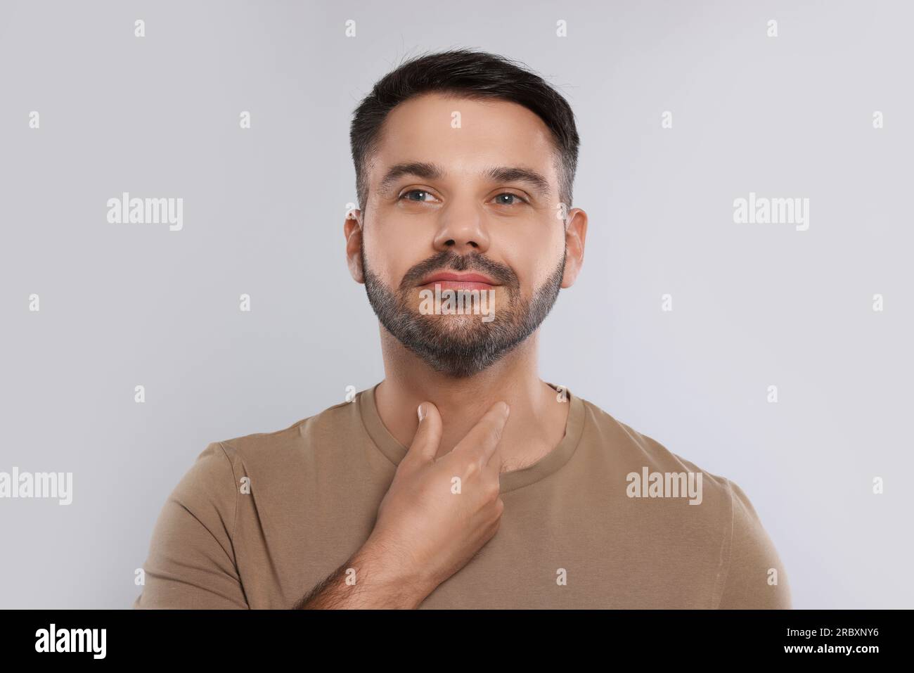 Endocrine system. Man doing thyroid self examination on light grey ...