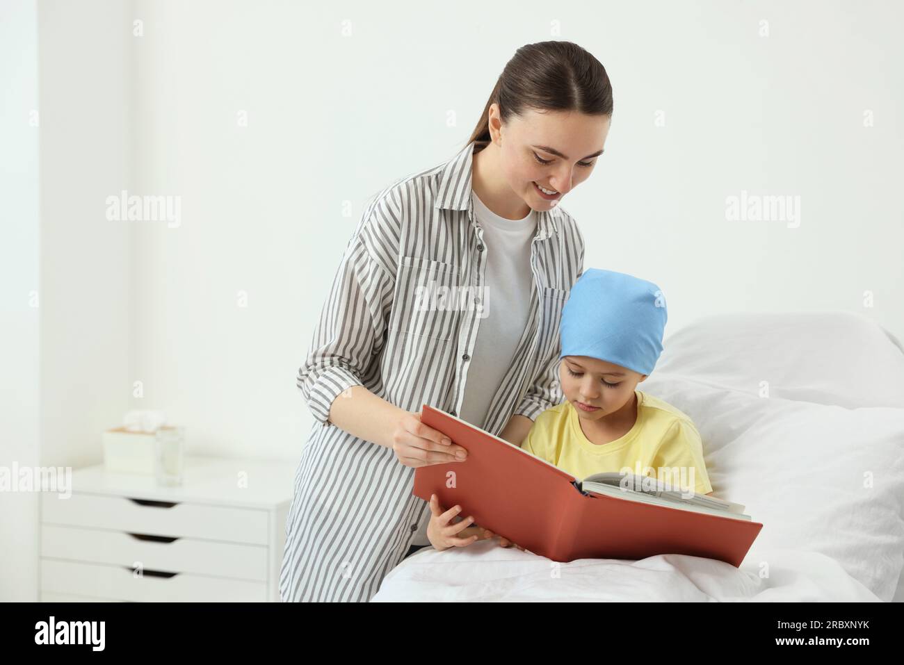 Childhood cancer. Mother and daughter reading book in hospital Stock ...