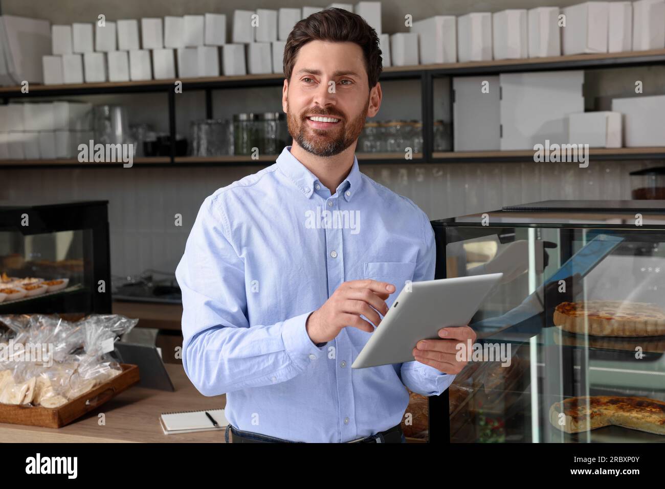 Happy business owner with tablet in bakery shop Stock Photo - Alamy
